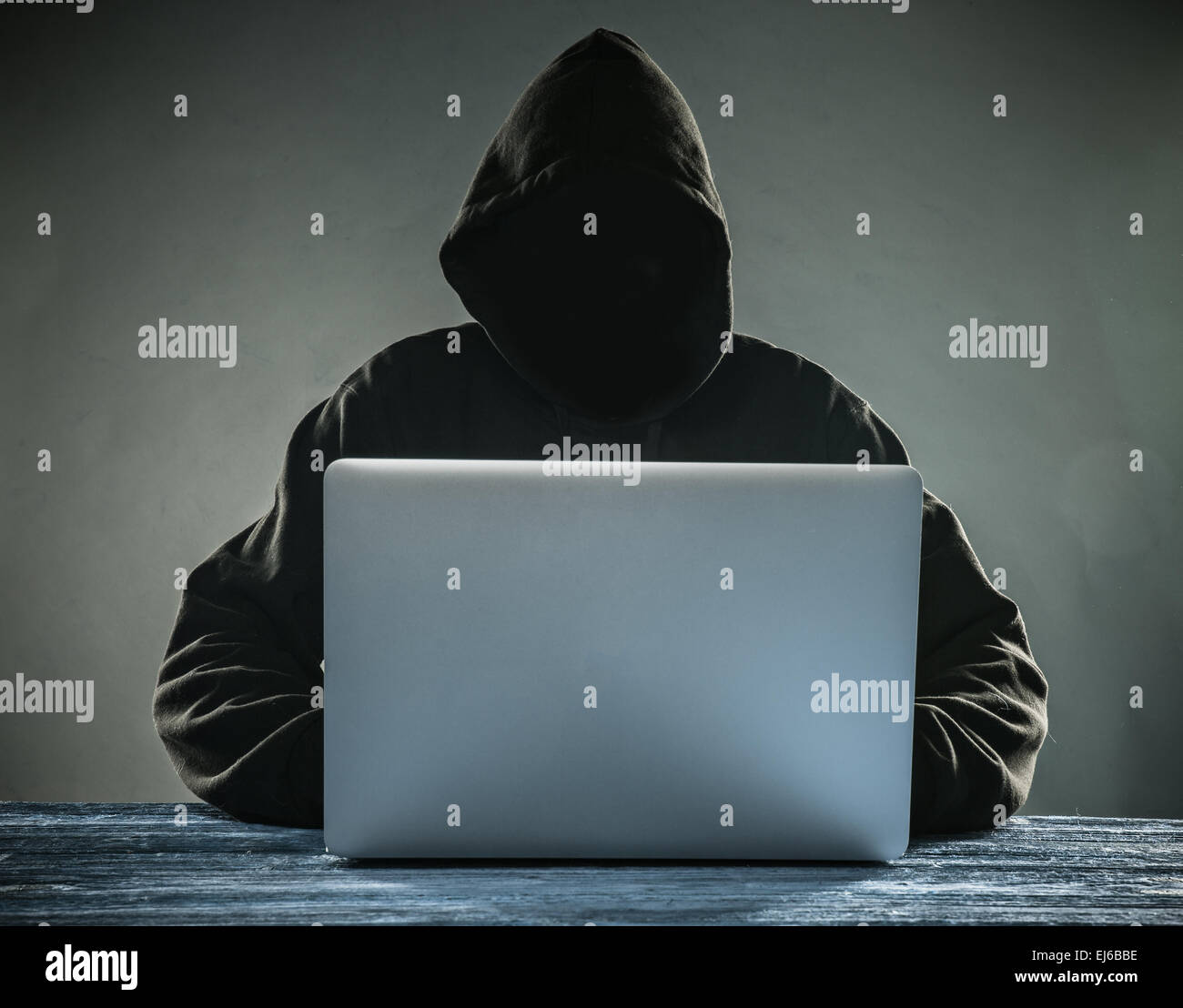 A hacker with a hood with laptop. Online network danger Stock Photo - Alamy