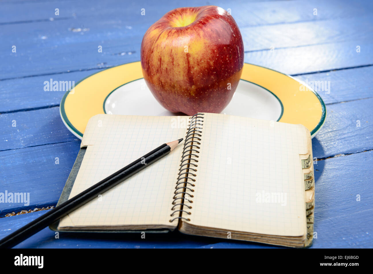 Apple and notebook on a table with pencil Stock Photo - Alamy