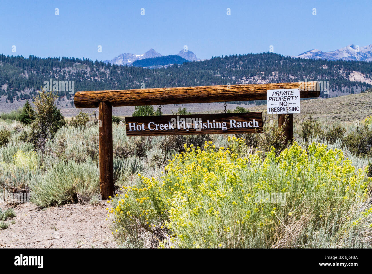 A sign for the Hot Creek Fly Fishing Ranch with Mammoth Lakes visible ...