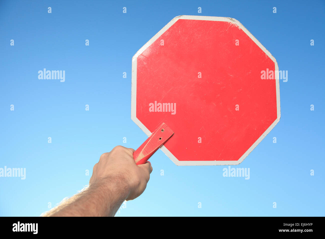 A hand holding a stop sign blue sky background Stock Photo - Alamy
