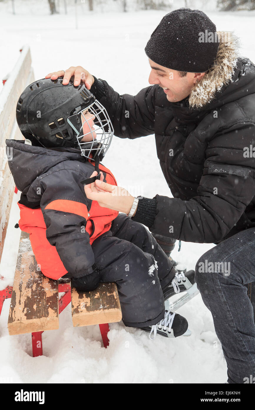 father help his child to put his helmet Stock Photo - Alamy