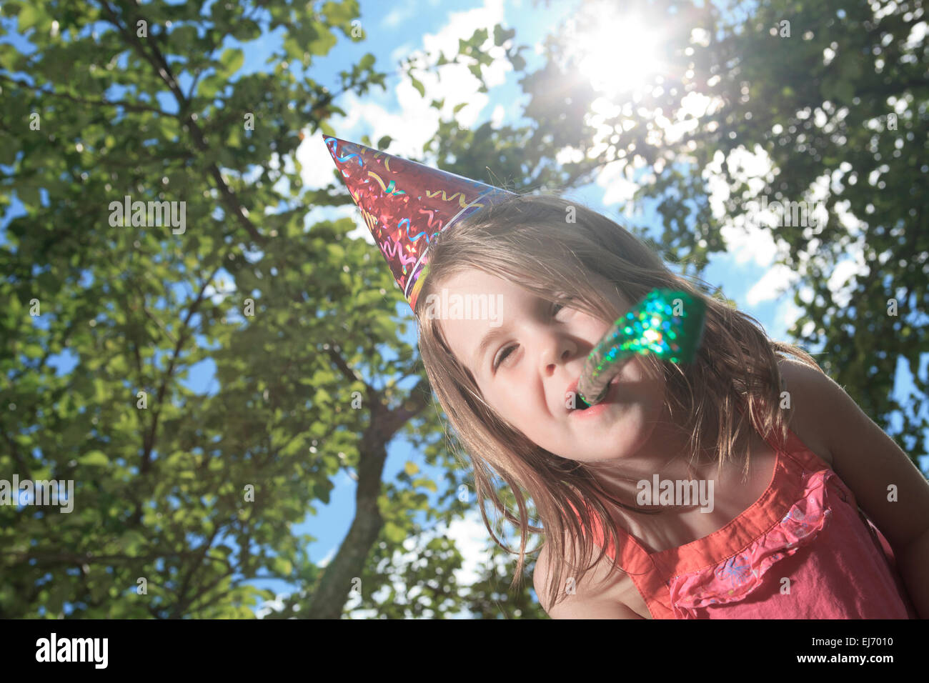 little girl outside with birthday hat and trumpet Stock Photo - Alamy