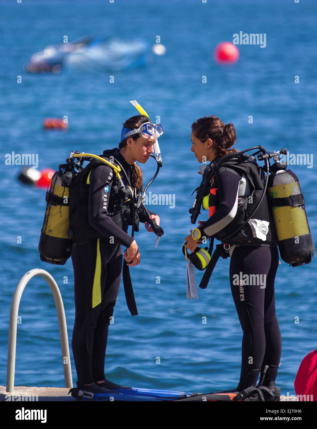 Two scuba divers, probably an instructor and a student, prepare to dive ...