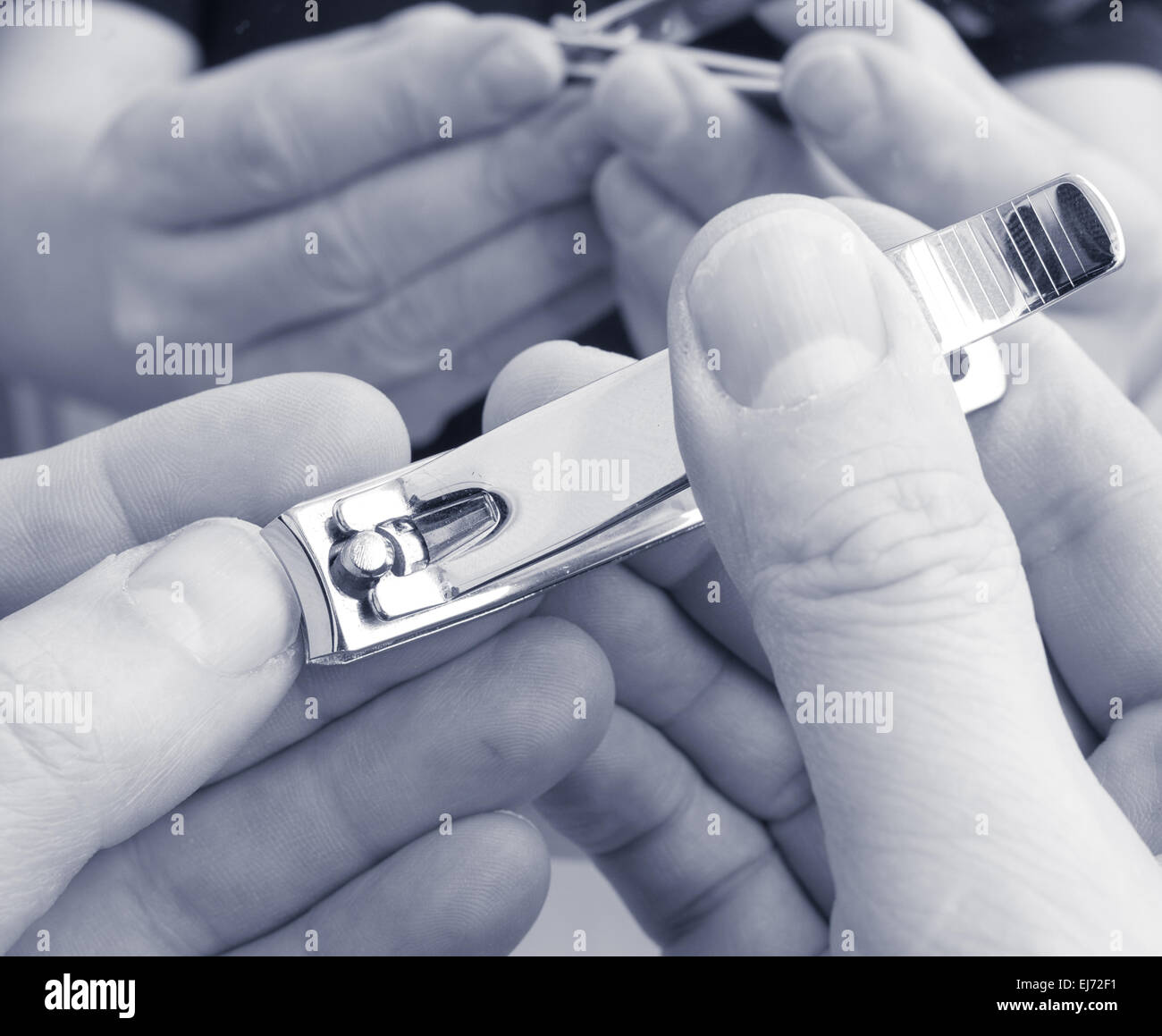 Close-up, man cuts finger nails, blue tinted black and white image ...
