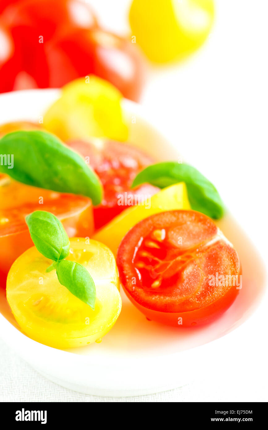 Assorted colorful red and yellow cherry tomatoes in plate on white ...