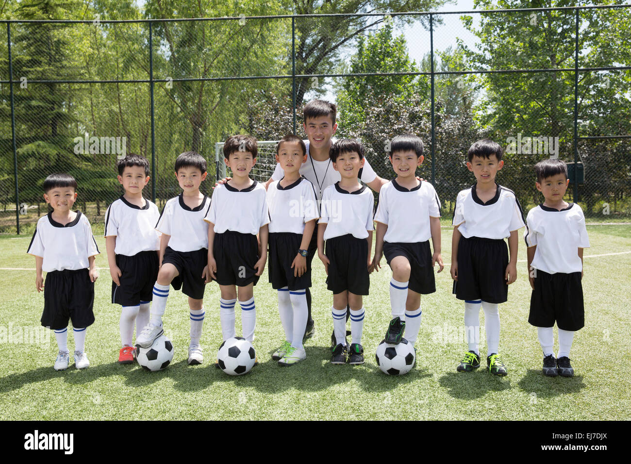 The football coach and the boys stand in a row in the football field ...