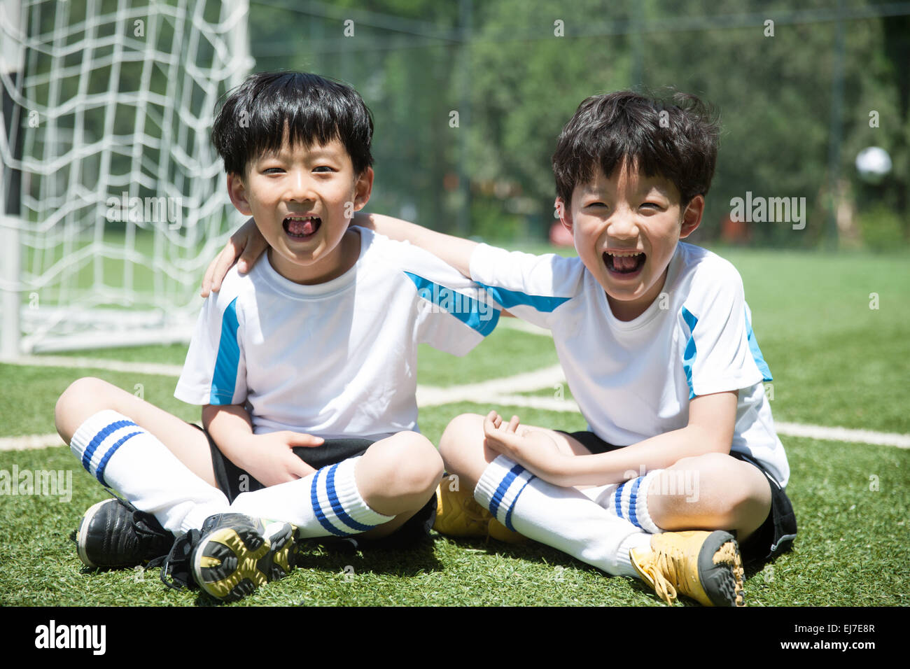 The two boys hug shoulders sitting on the football field Stock Photo ...
