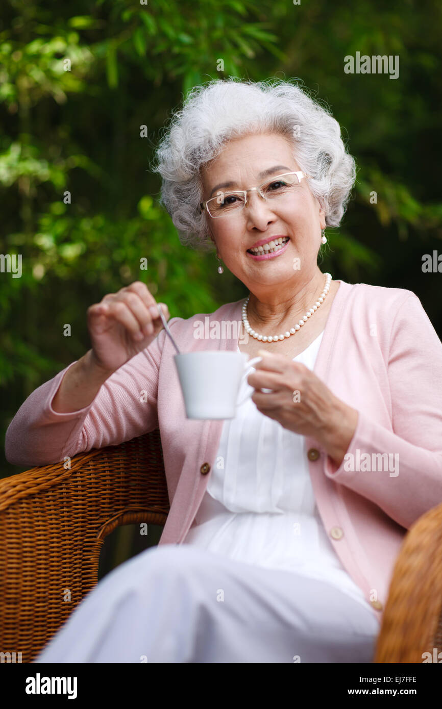 The old woman to drink coffee in the garden Stock Photo - Alamy