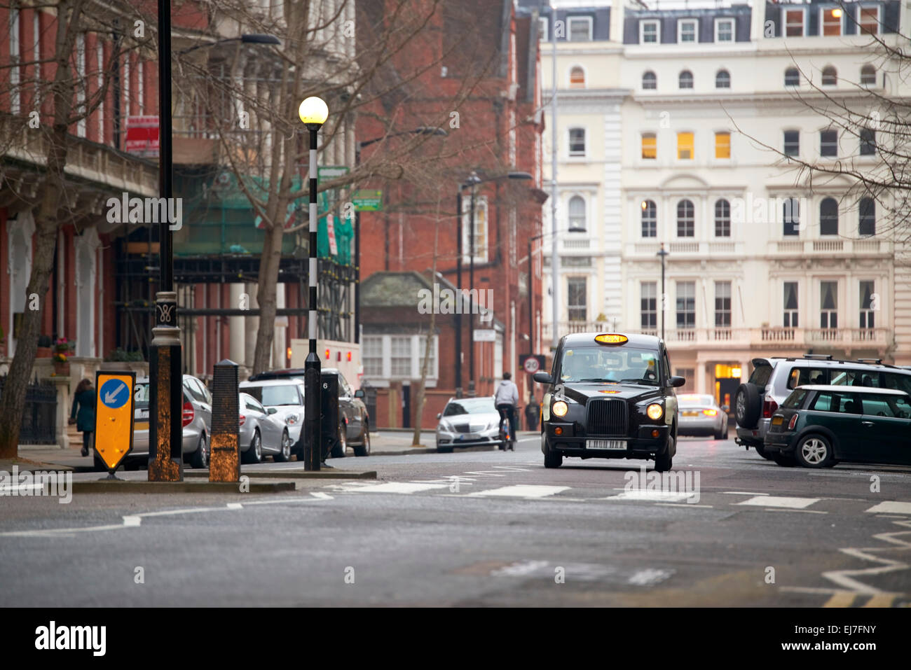 Famous London black cab in residential road in early evening. There are ...