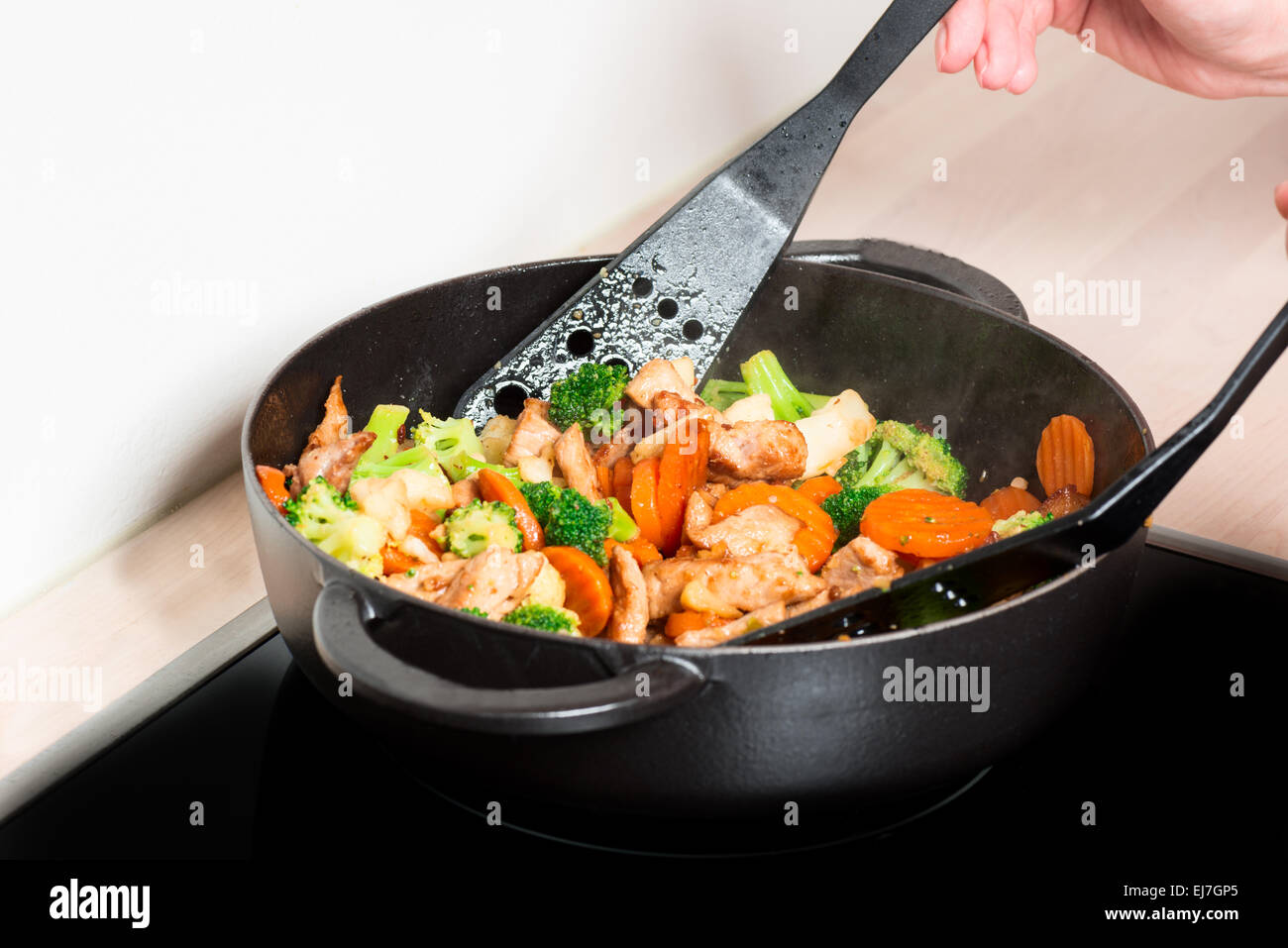Frying meet and vegies in skillet with hands Stock Photo - Alamy
