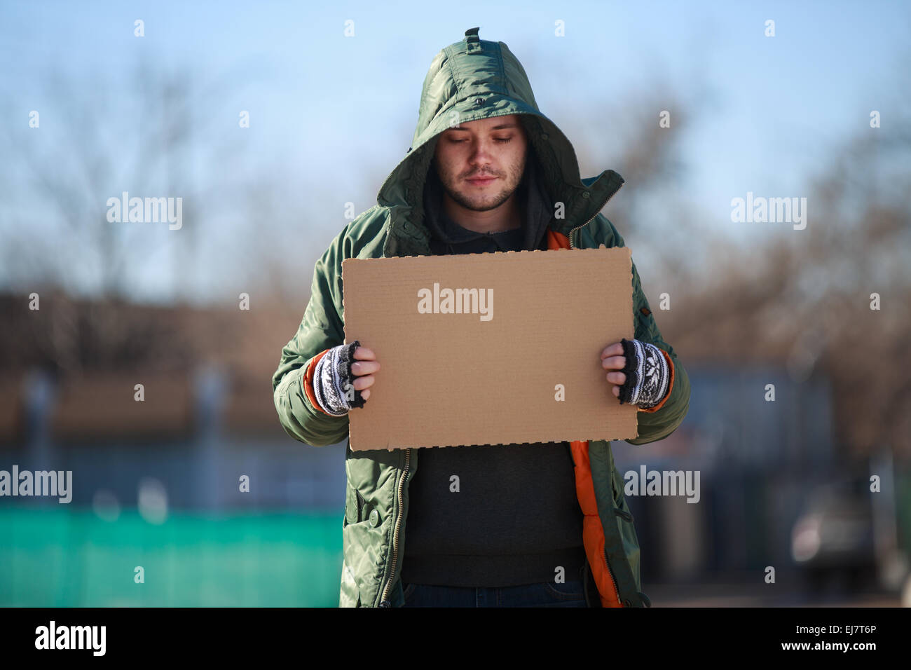 Homeless person with blanck cardboard. Focused on cardboard Stock Photo ...