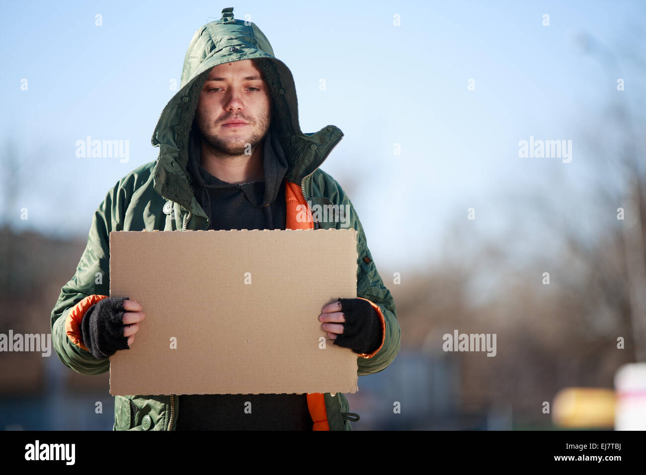 Homeless person with blanck cardboard. Focused on cardboard Stock Photo ...