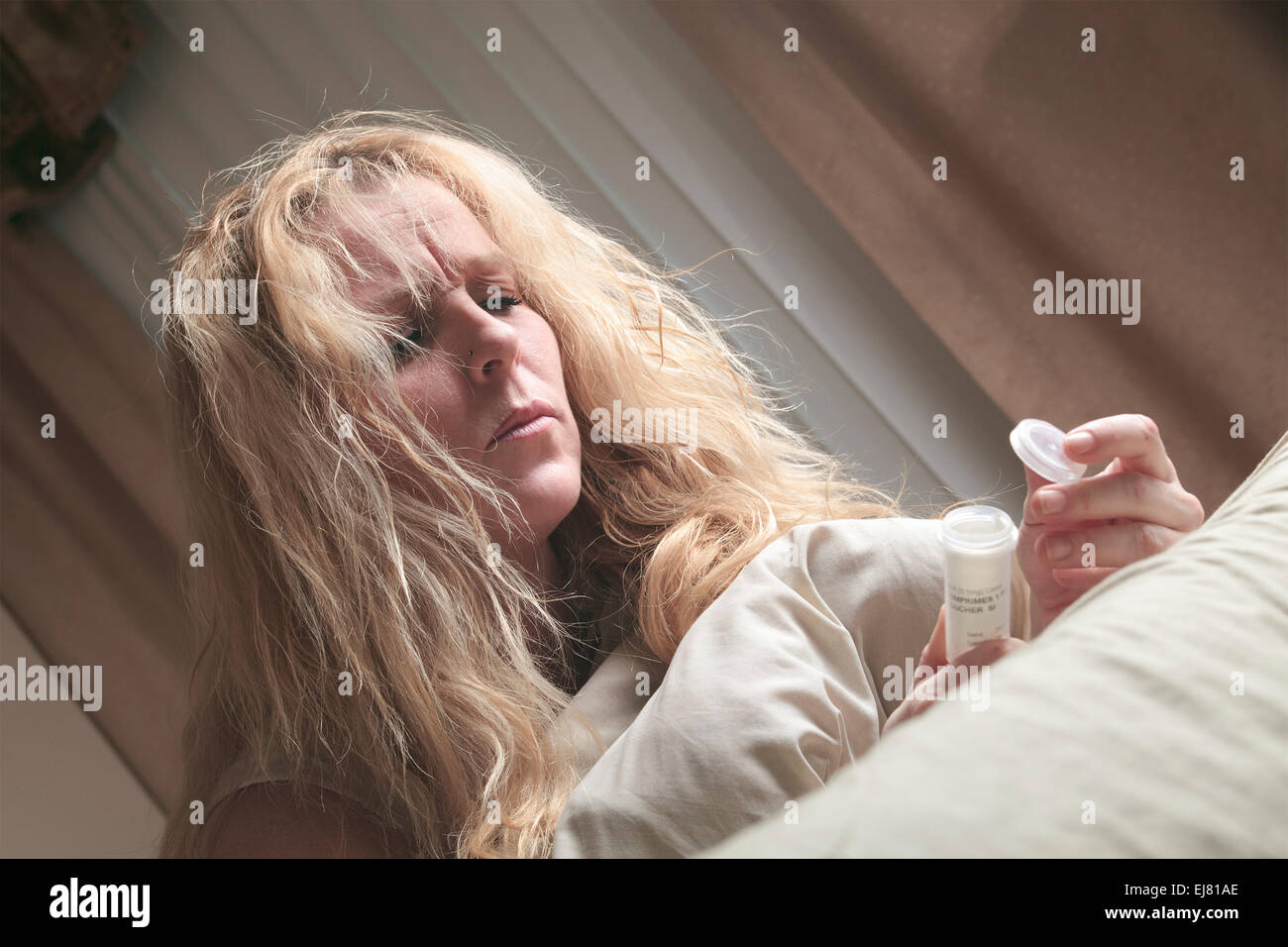 A sad woman taking medication on bed Stock Photo - Alamy