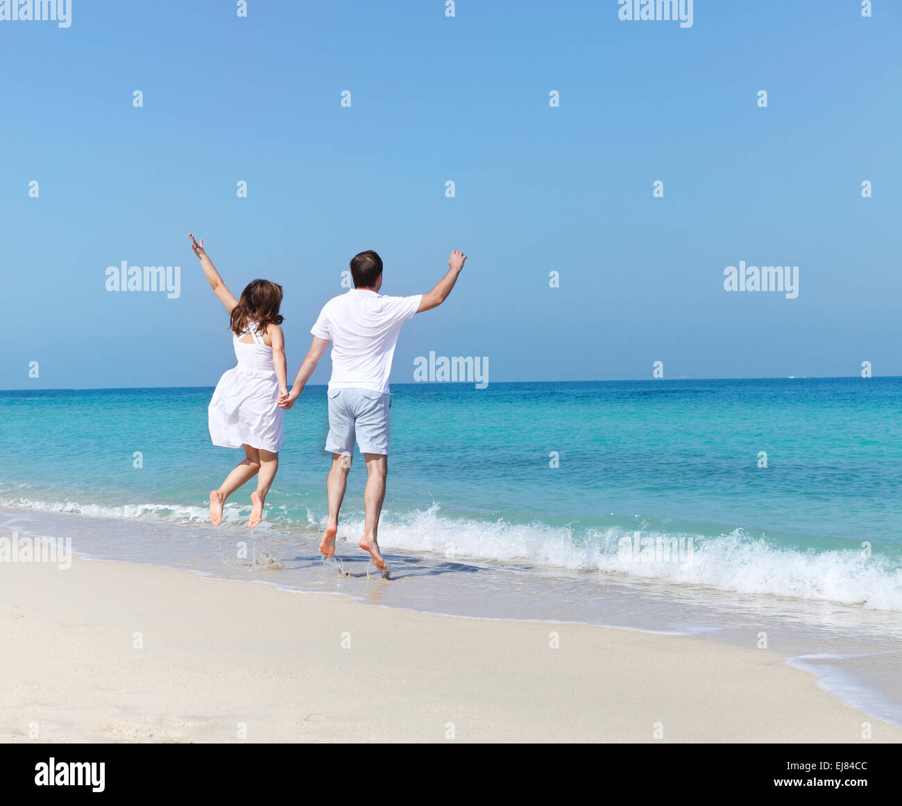 Young happy couple jumping on the beach Stock Photo - Alamy