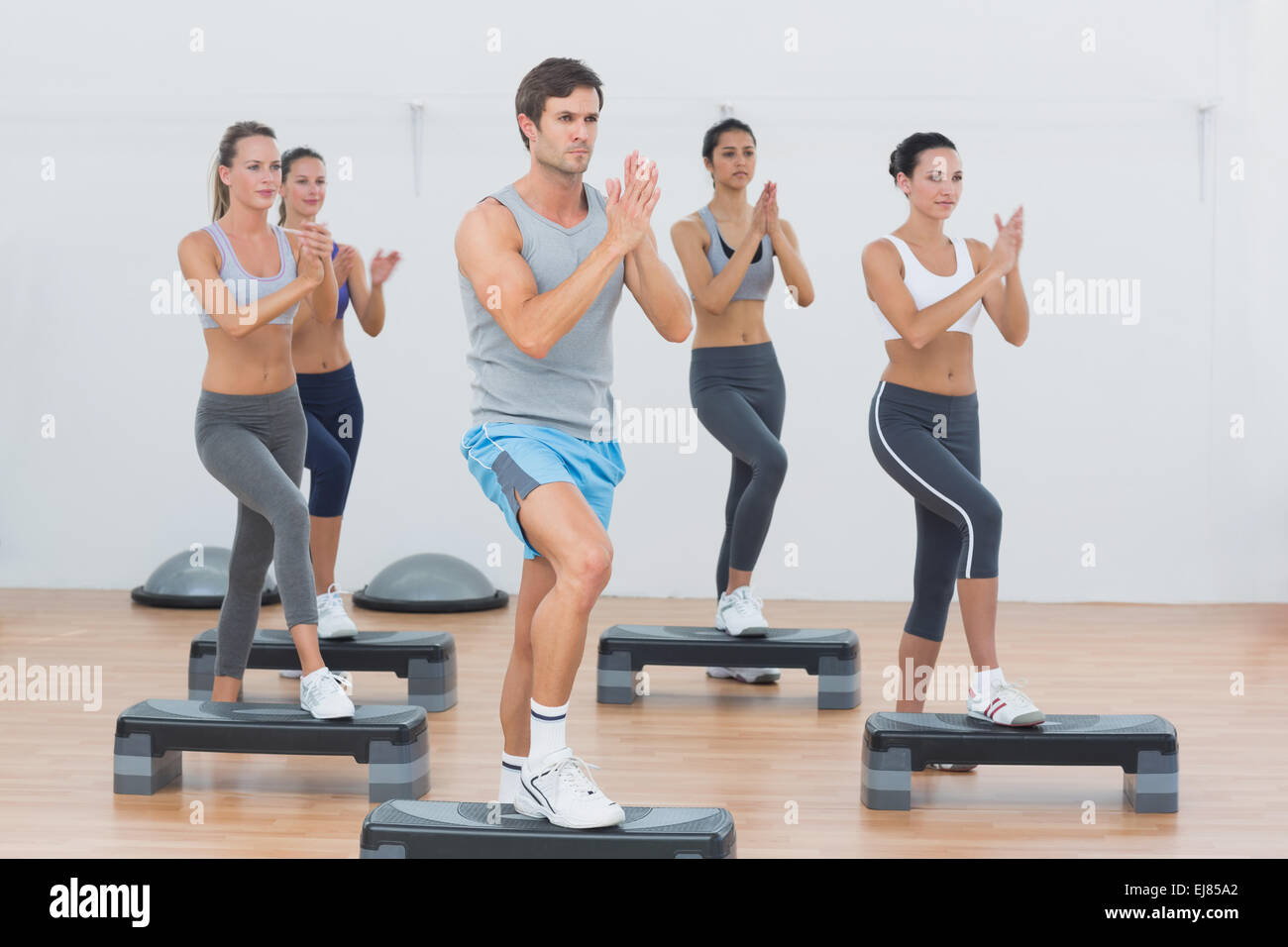 Instructor with fitness class performing step aerobics exercise Stock ...