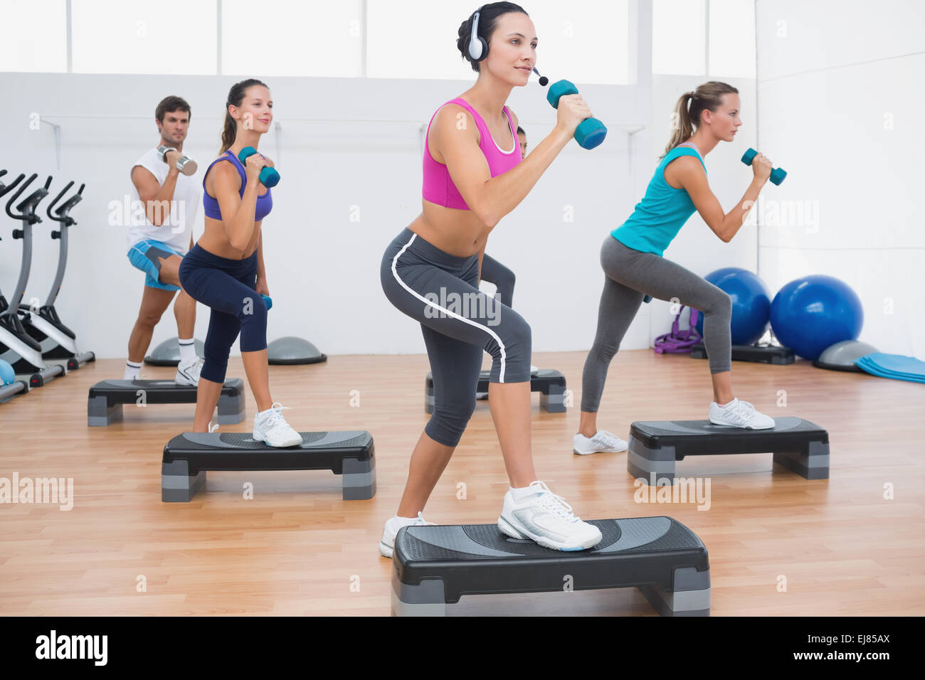 Class performing step aerobics exercise with dumbbells Stock Photo - Alamy