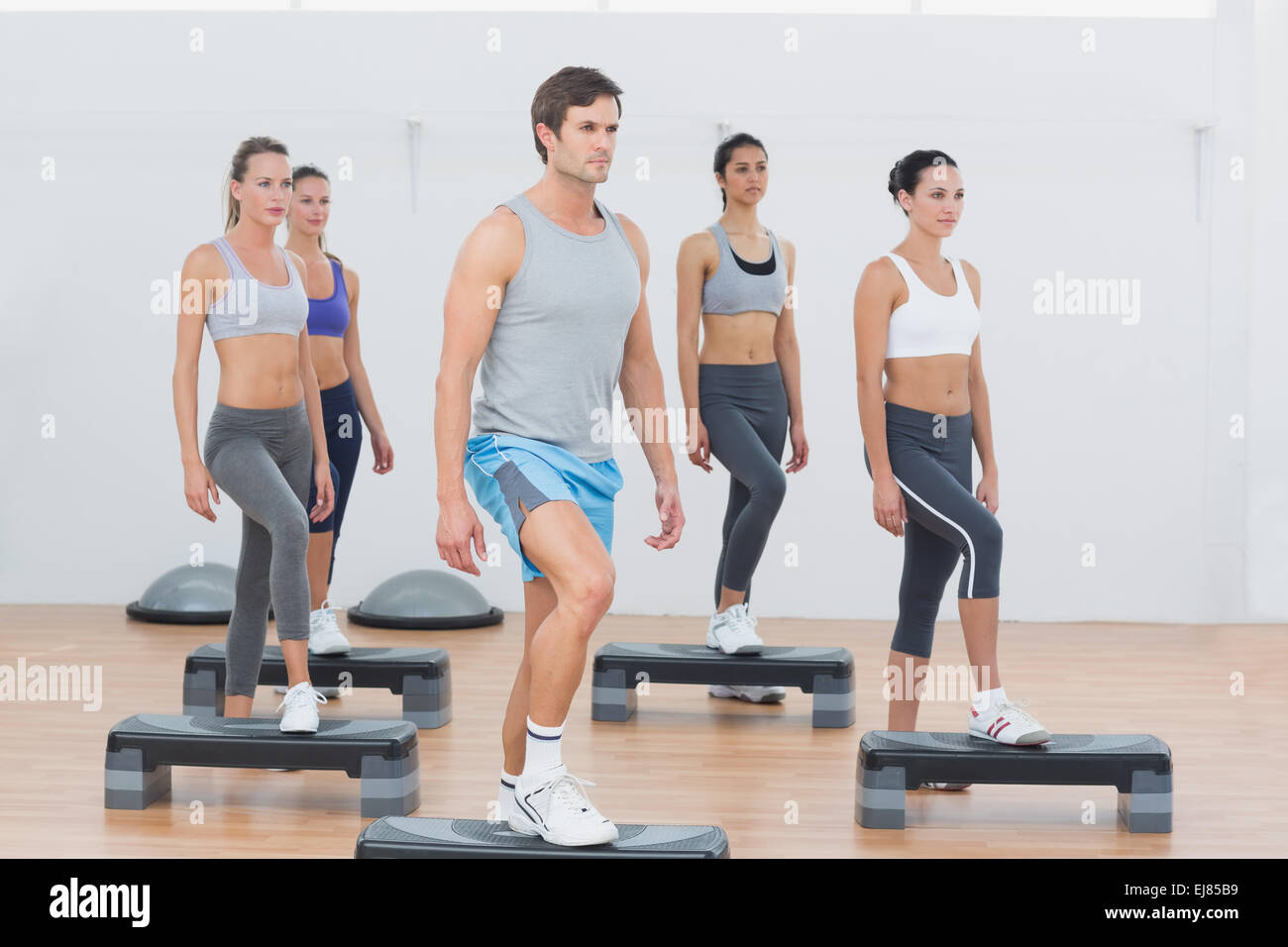 Instructor with fitness class performing step aerobics exercise Stock ...
