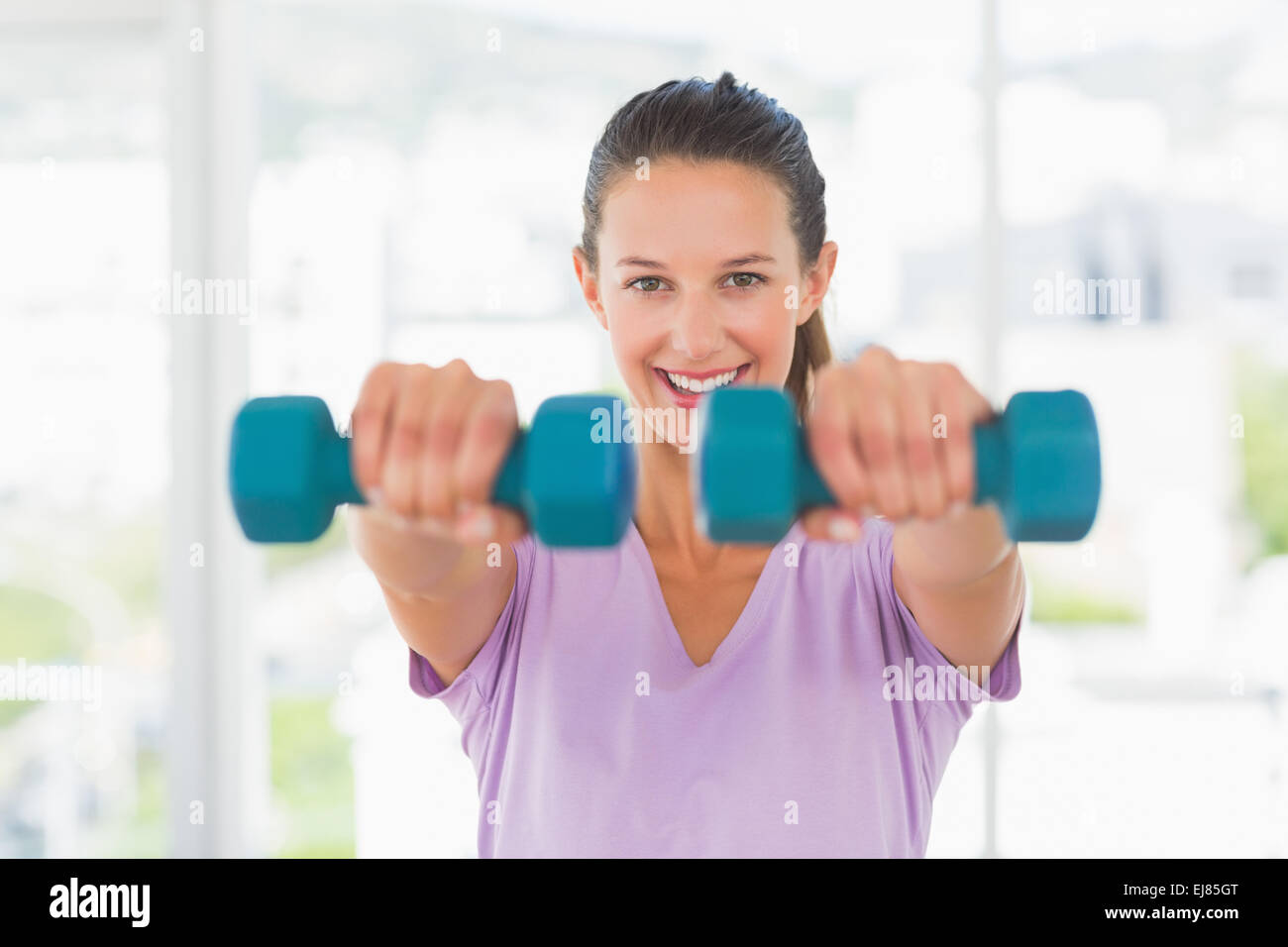 Smiling young woman lifting dumbbell weights Stock Photo - Alamy