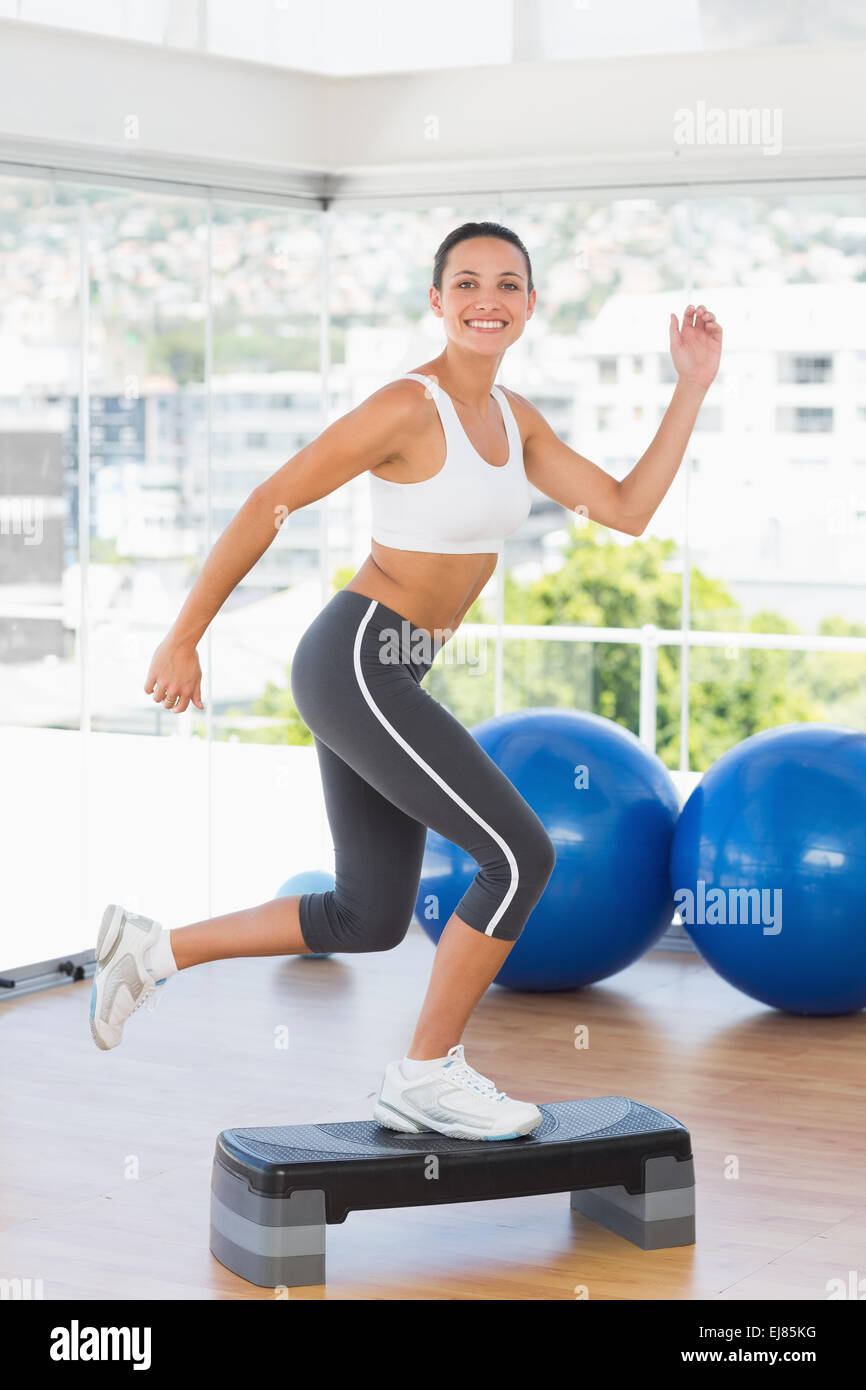 Fit young woman performing step aerobics exercise Stock Photo - Alamy