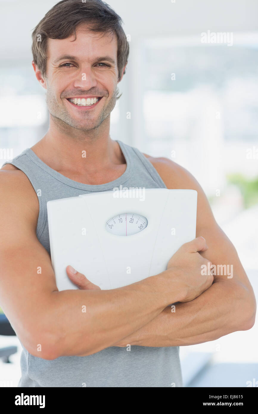 Fit young man with scale in bright exercise room Stock Photo - Alamy