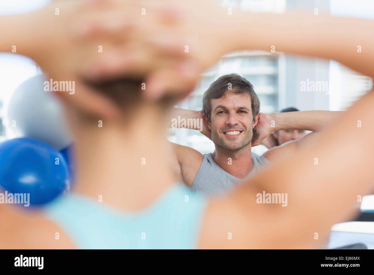 Smiling male with blurred people doing stretching exercises Stock Photo ...