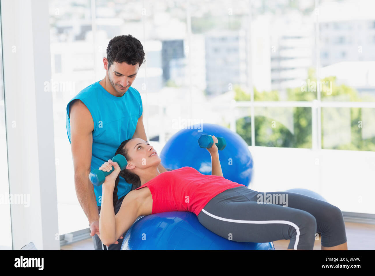 Trainer helping woman with her exercises at gym Stock Photo - Alamy