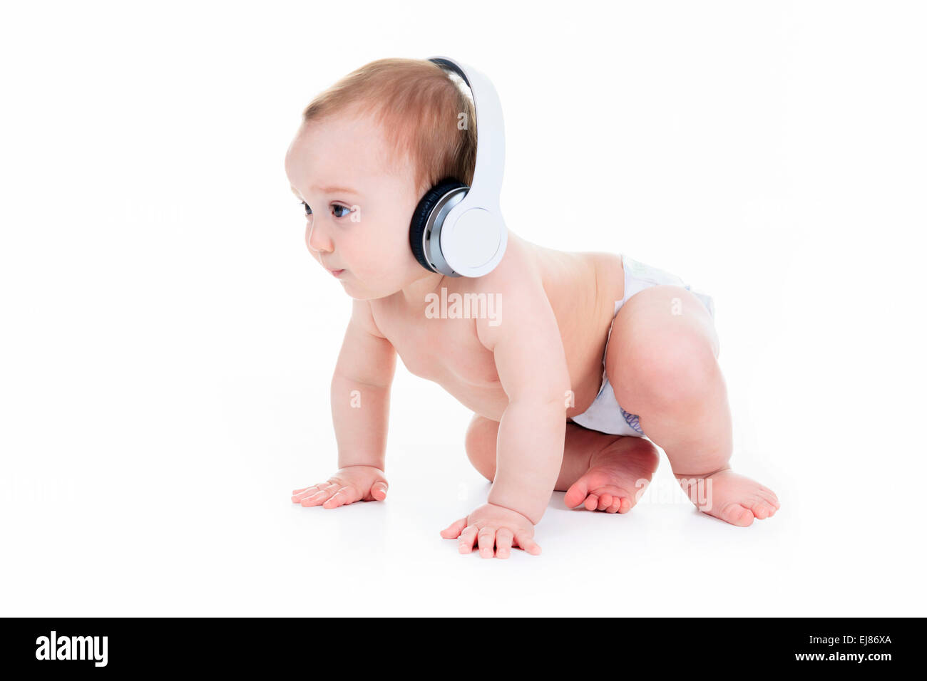 young baby is sitting on a white isolated background listening Stock ...