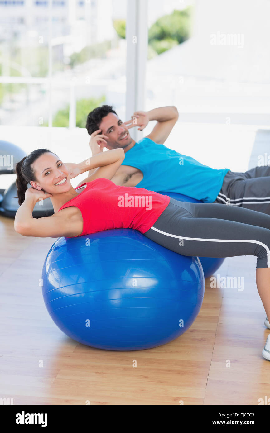 Fit young couple exercising on fitness balls at gym Stock Photo - Alamy