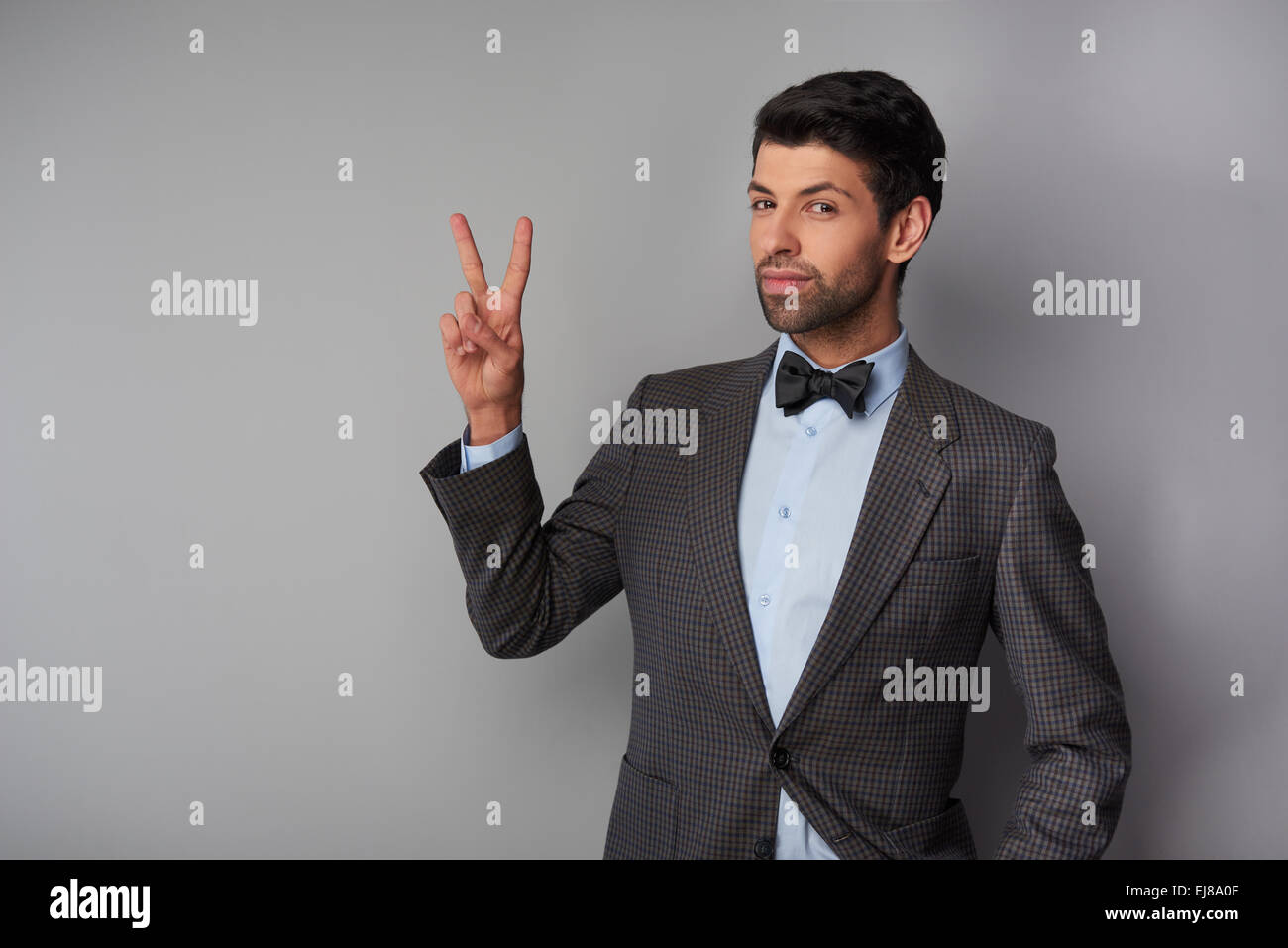 Man showing victory sign and looking at camera Stock Photo - Alamy