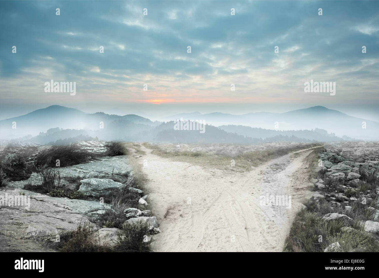 Dusty path leading to misty mountains Stock Photo - Alamy