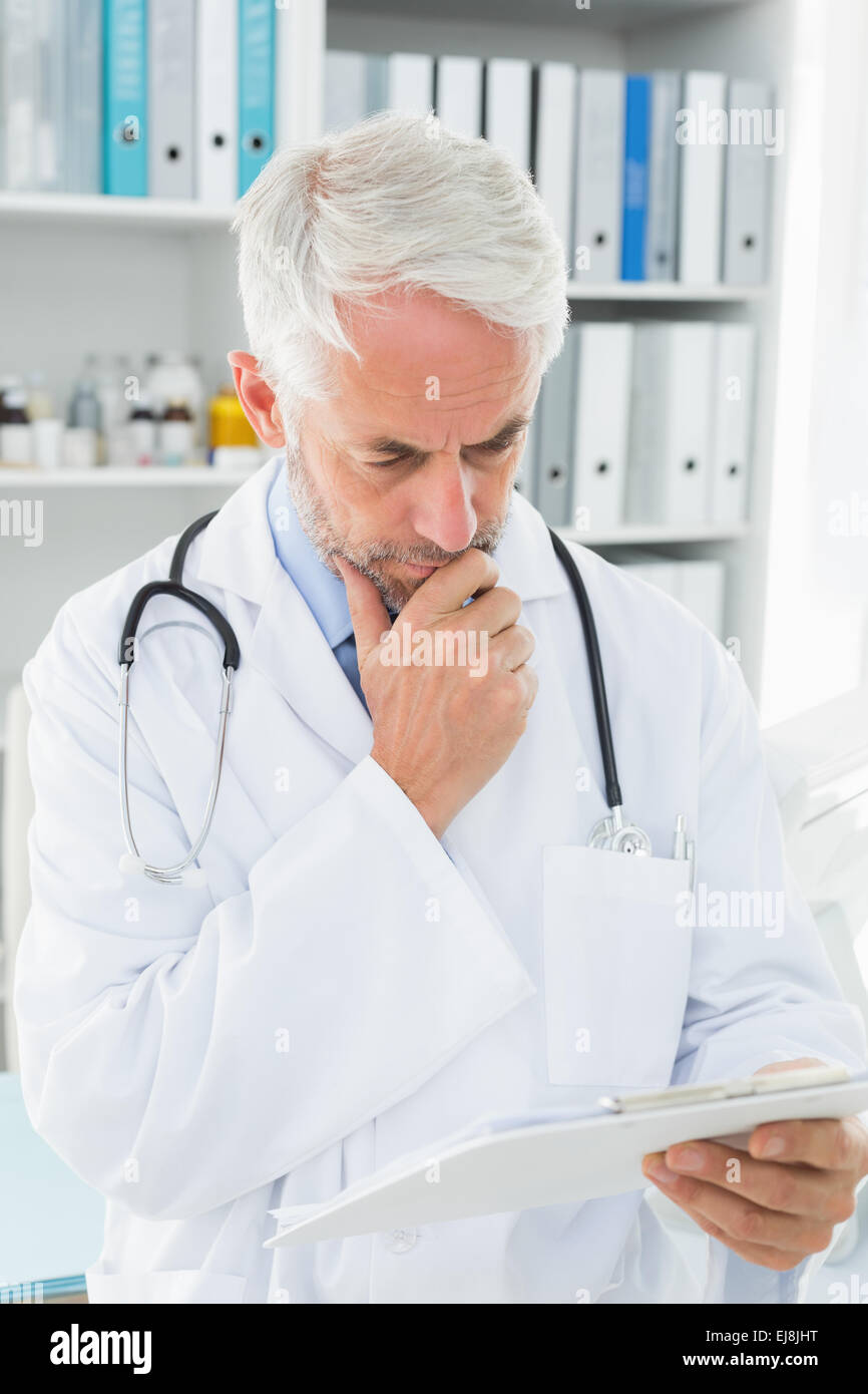 Concentrated male doctor looking at reports Stock Photo - Alamy