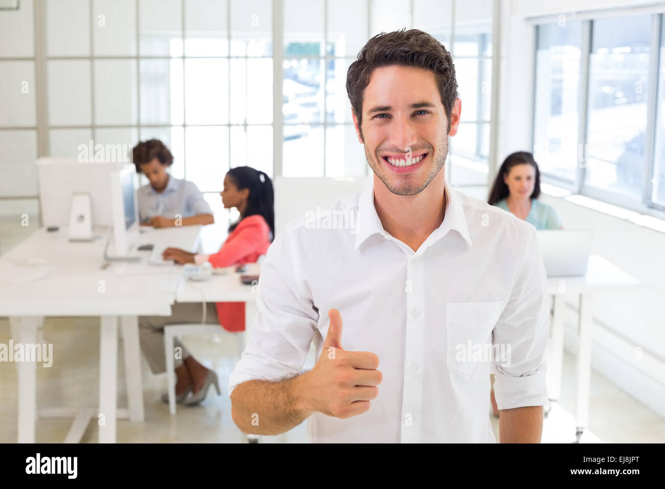 Smiling worker giving thumbs up Stock Photo - Alamy