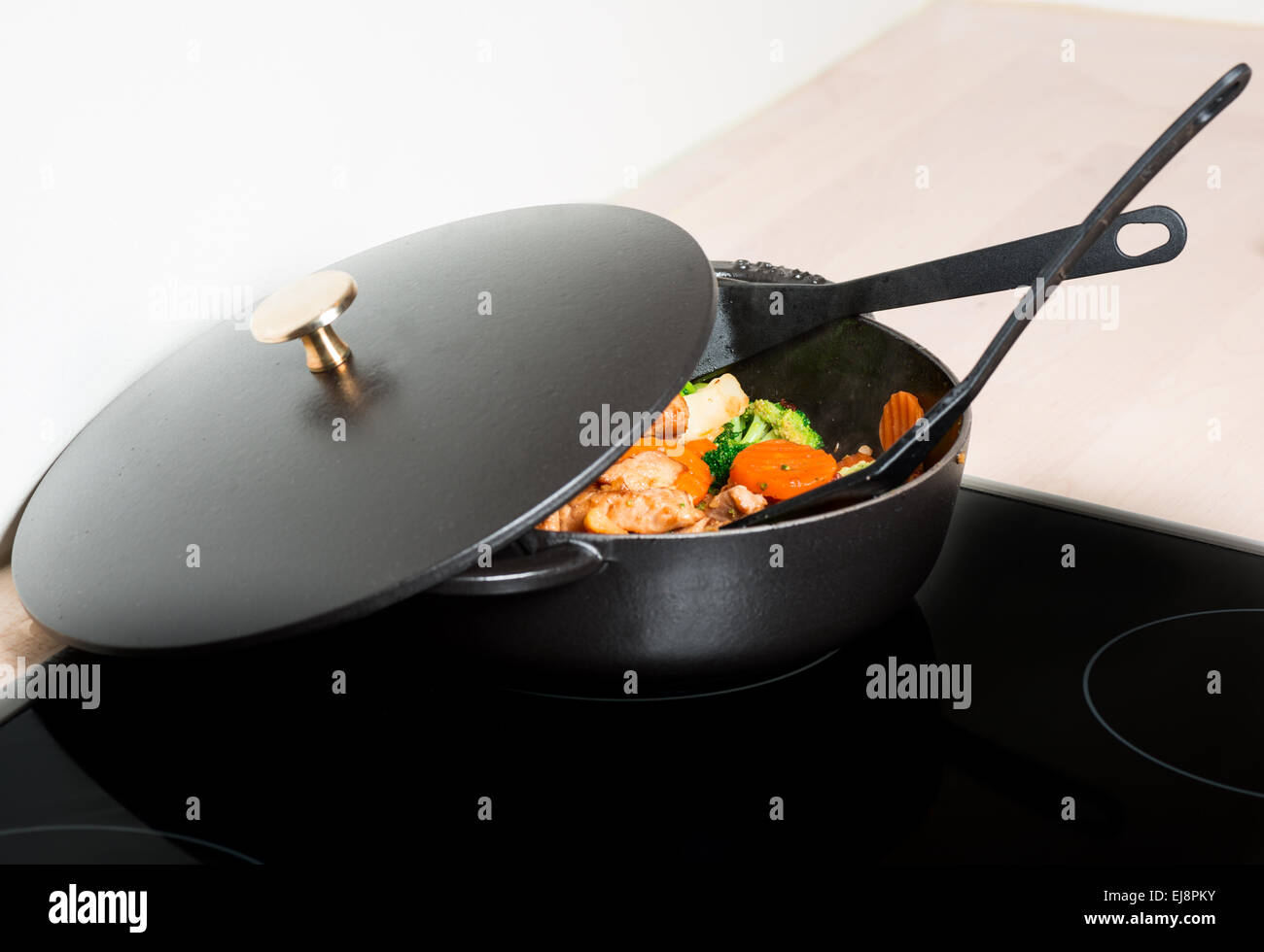 Frying meet and vegies in skillet with utencils Stock Photo - Alamy
