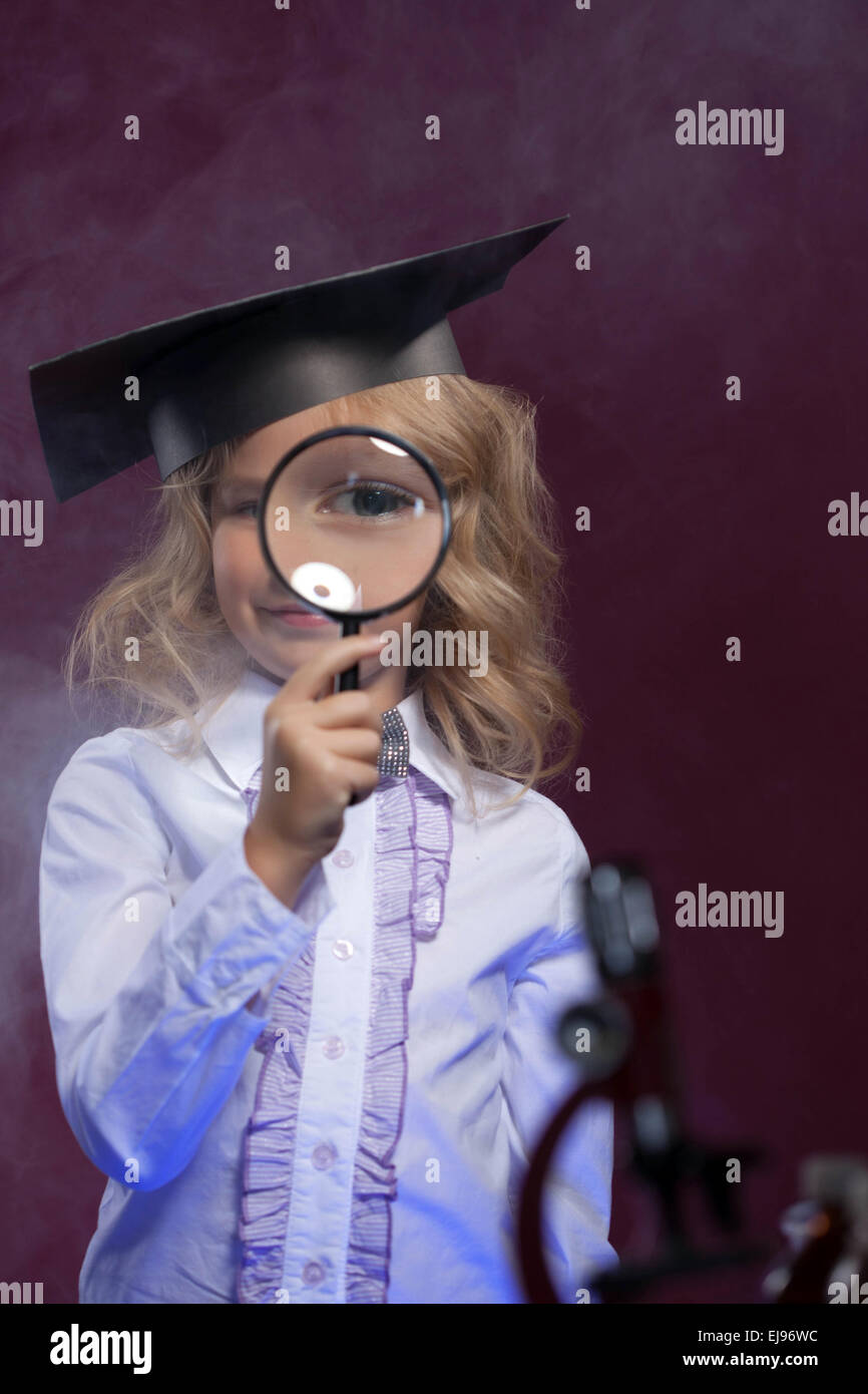 Curious girl looking through magnifying glass Stock Photo - Alamy