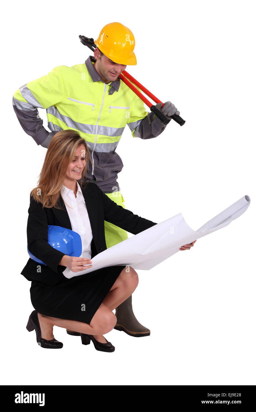 Architect kneeling by builder with plans Stock Photo - Alamy