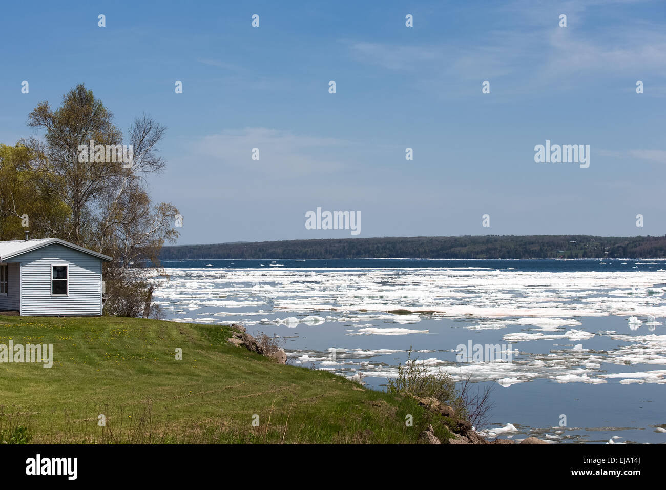Ice breaking up on a bay in the Spring. Small house overlooking the ...