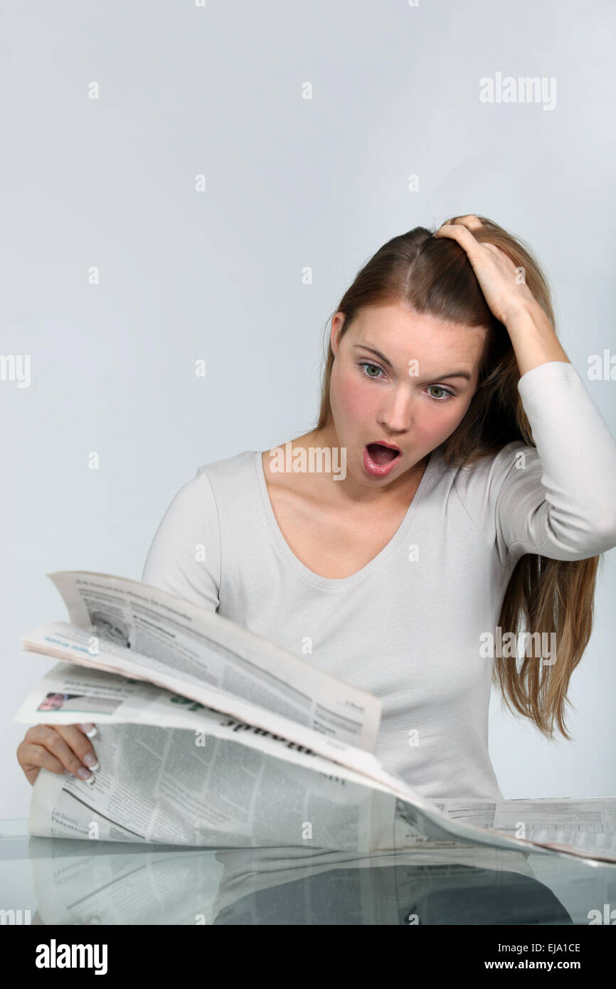 Shocked woman reading a newspaper Stock Photo - Alamy