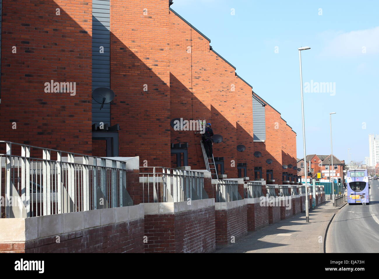 A workman up a ladder repairing a satellite dish on a property at ...