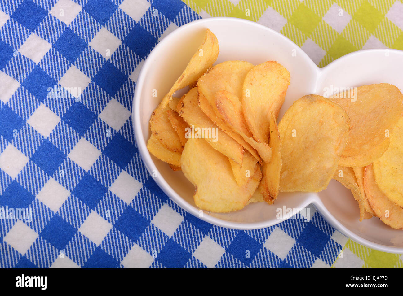 Close-up of fresh, crispy potato chips in a wooden bowl on a white ...