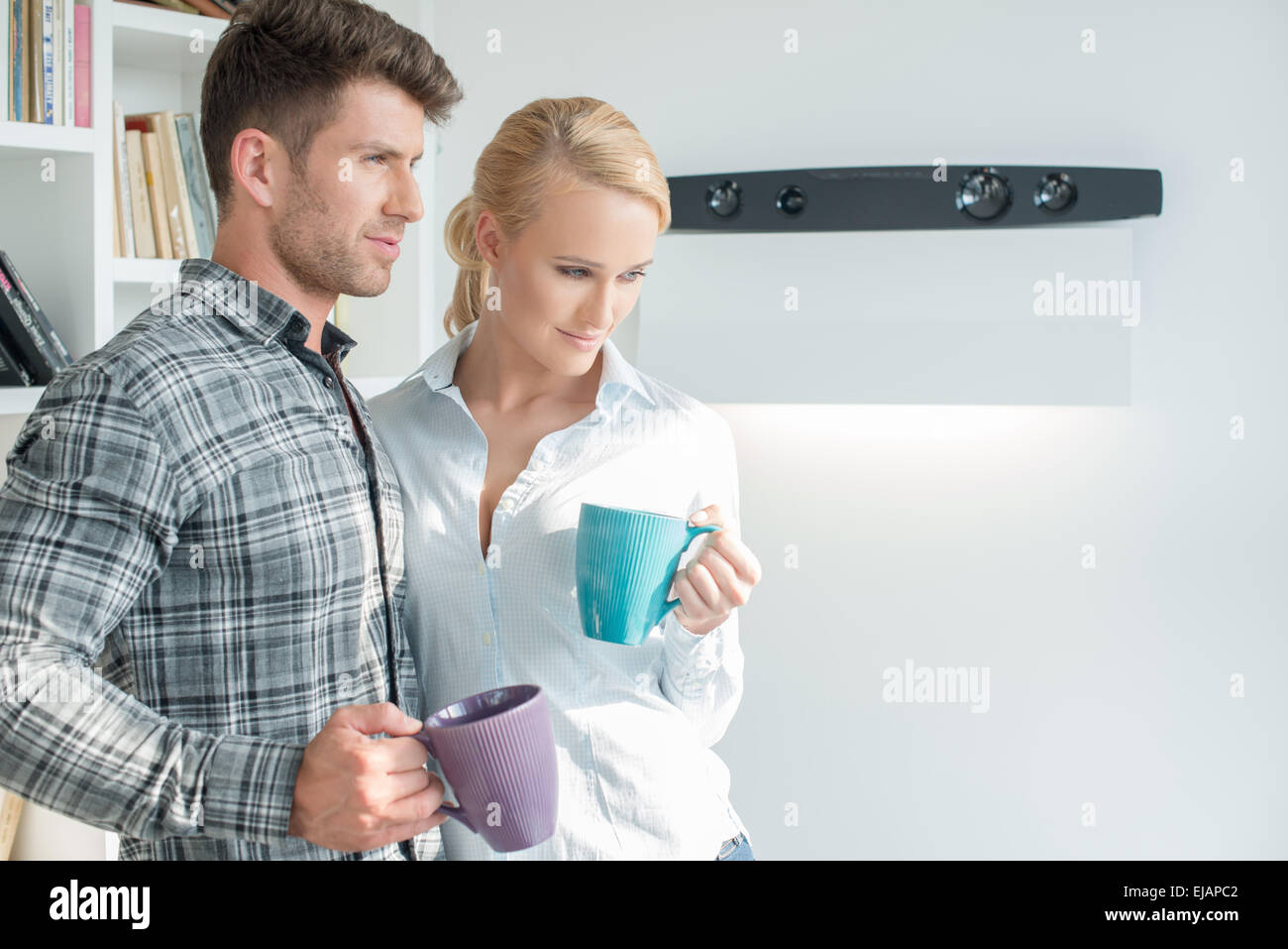 Young couple standing drinking coffee Stock Photo - Alamy