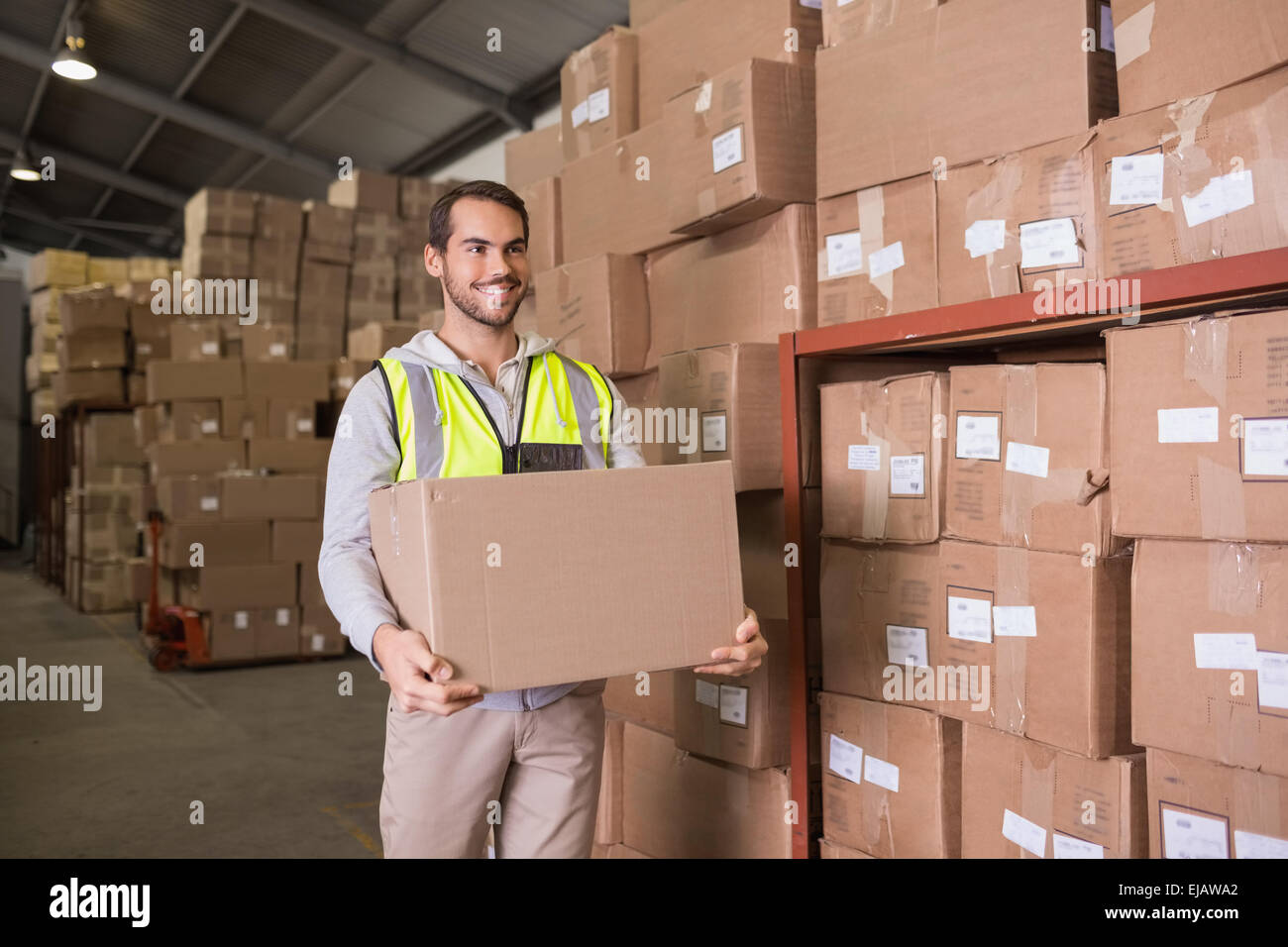 Worker carrying box in warehouse Stock Photo - Alamy