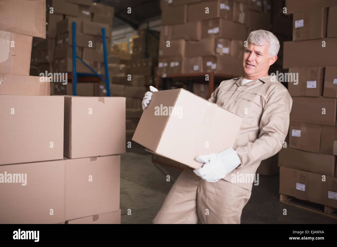 Worker carrying box in warehouse Stock Photo - Alamy