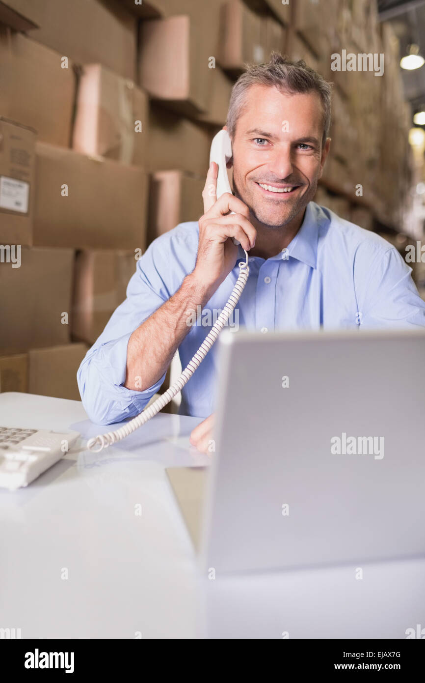 Warehouse manager using telephone and laptop Stock Photo - Alamy