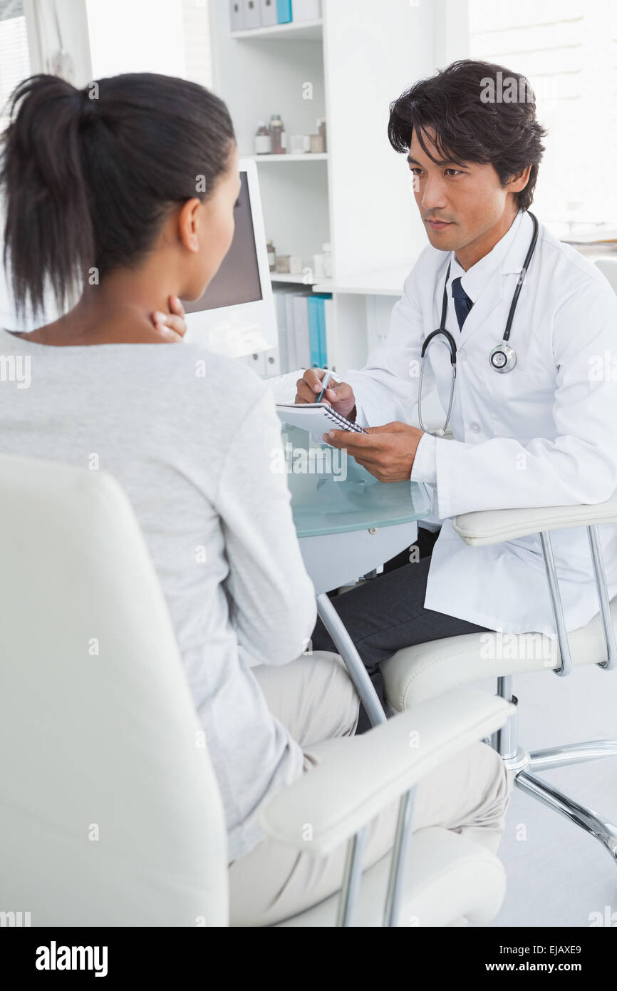 Doctor taking notes from patient Stock Photo - Alamy