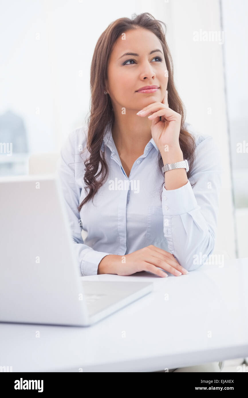 Pretty businesswoman thinking at her desk Stock Photo - Alamy