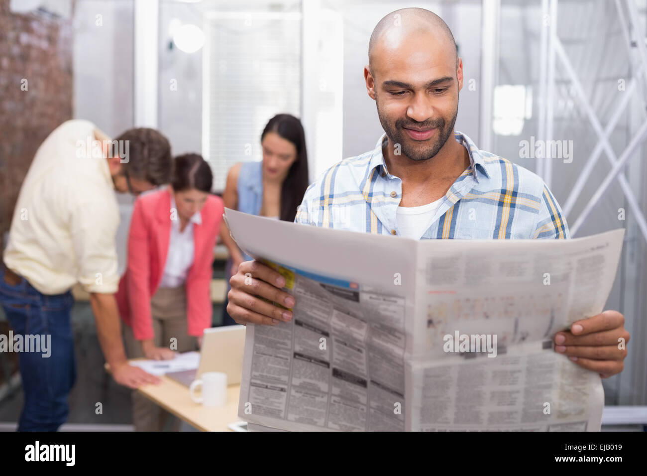 Smiling man reading the newspaper Stock Photo - Alamy