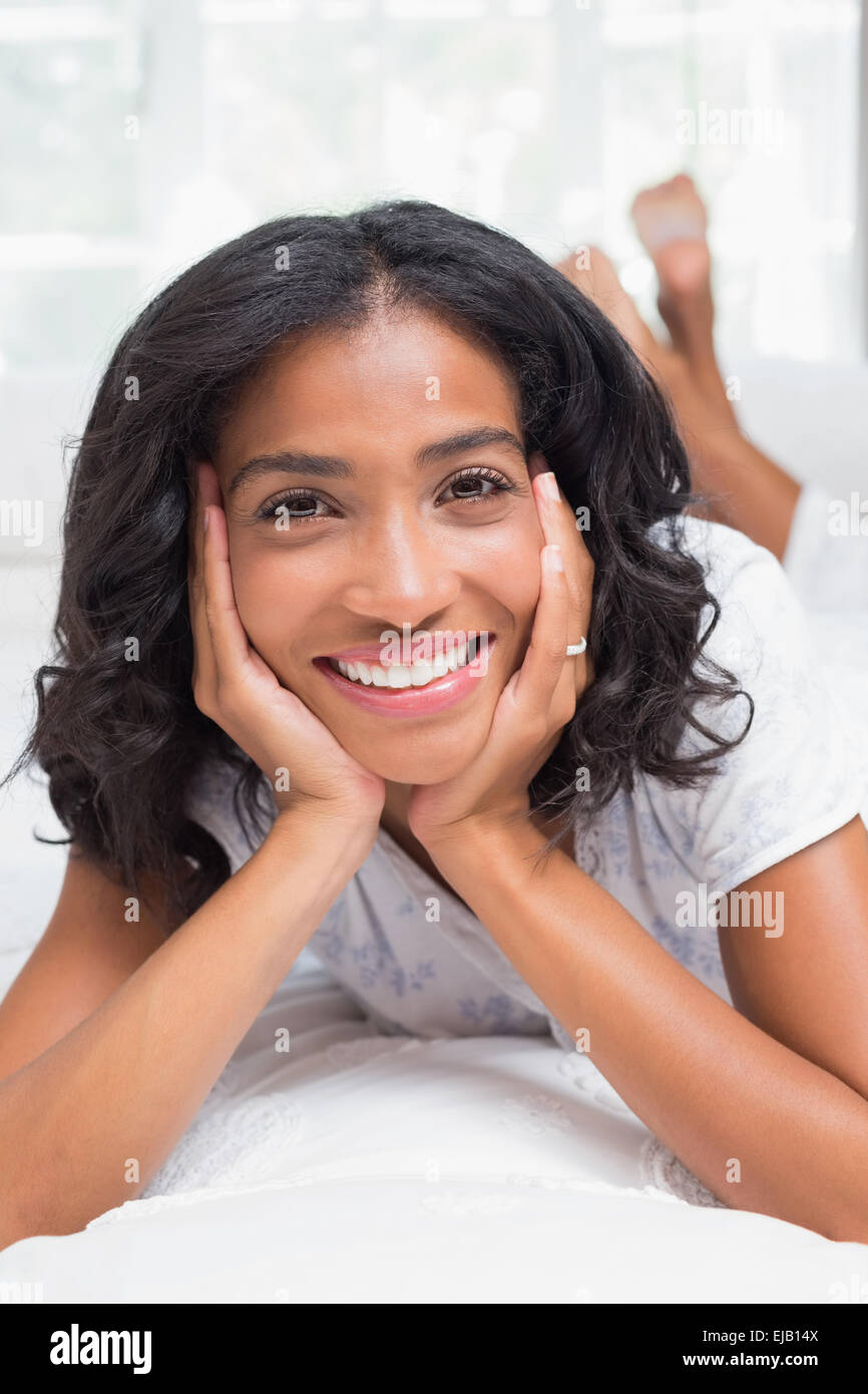 Pretty woman smiling at camera lying on bed Stock Photo - Alamy