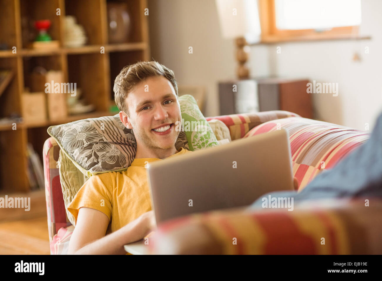 Young man using laptop on his couch Stock Photo - Alamy