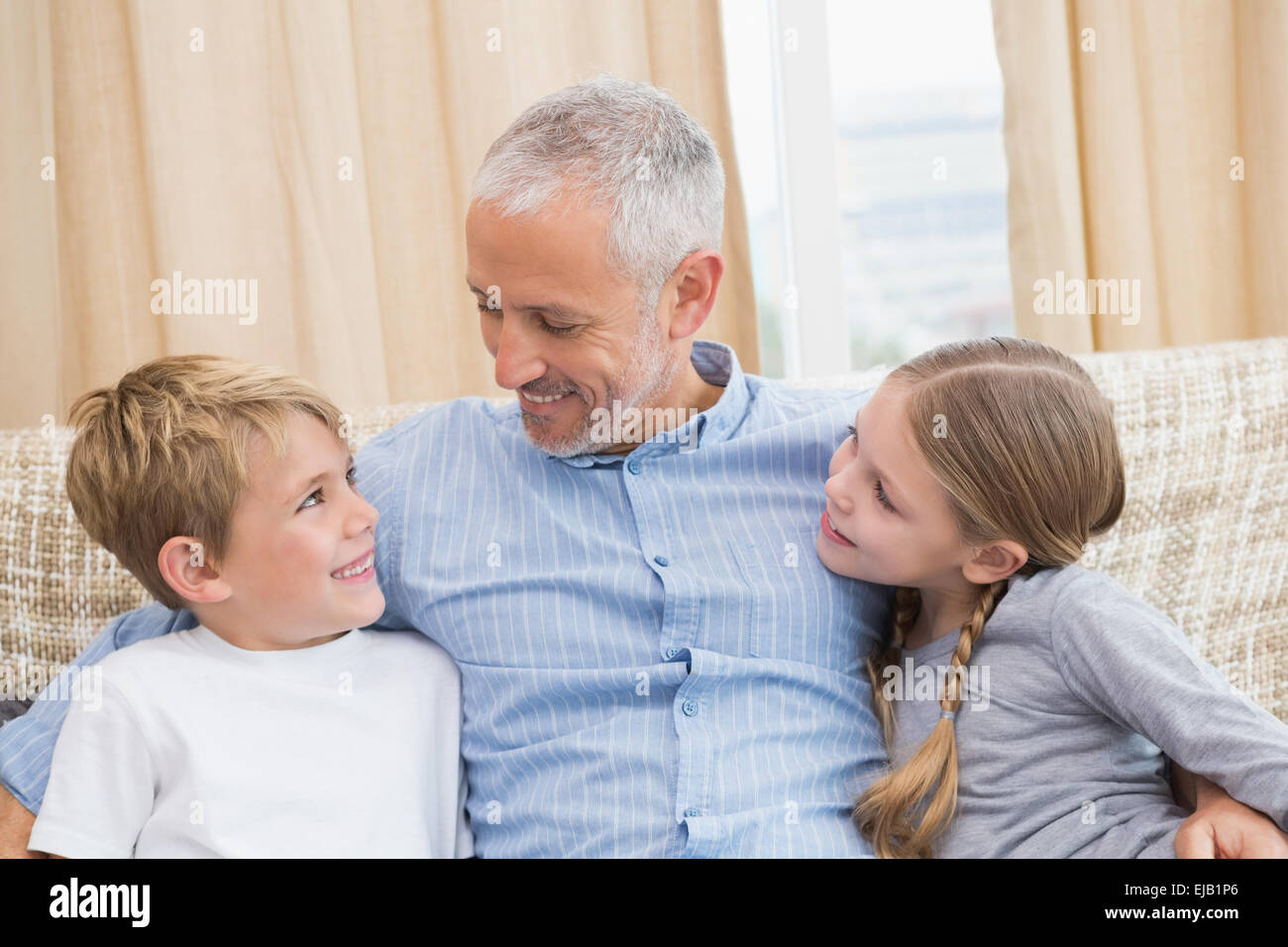 Father smiling with his children on sofa Stock Photo - Alamy