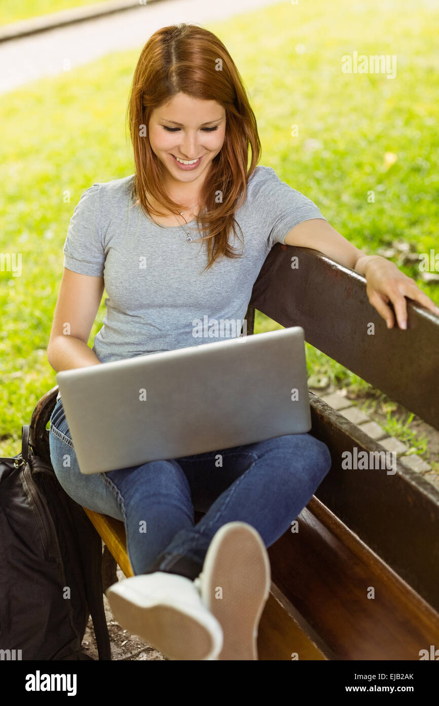 Happy girl sitting on bench using laptop Stock Photo - Alamy